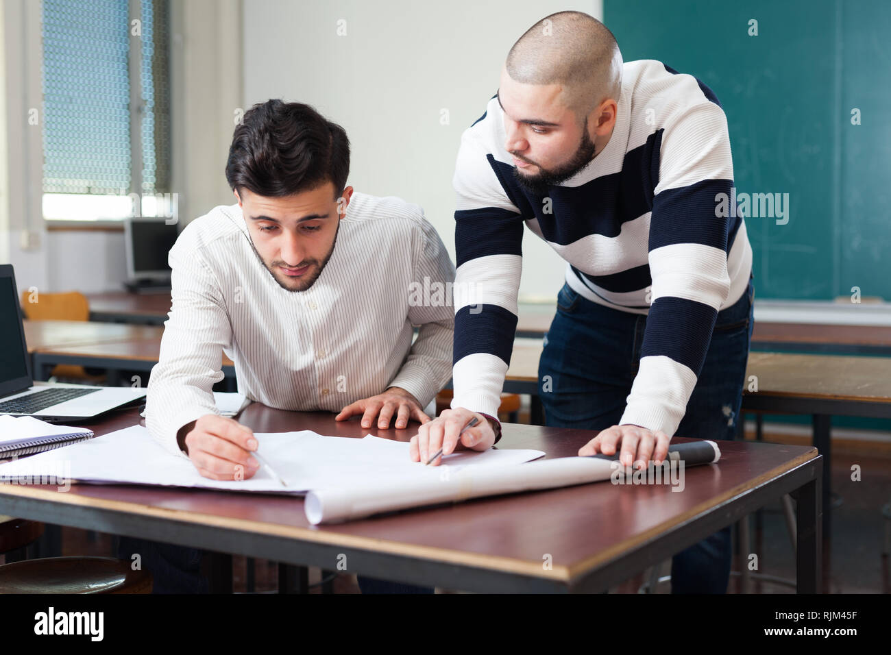 Two male university students sitting at desk preparing for exams ...