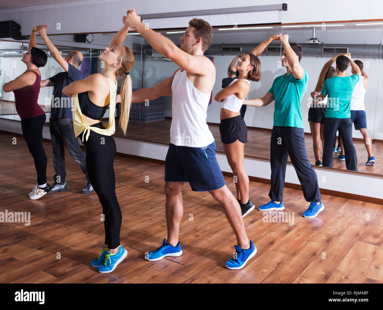 Young positive girls and men learning salsa at dance hall Stock Photo ...
