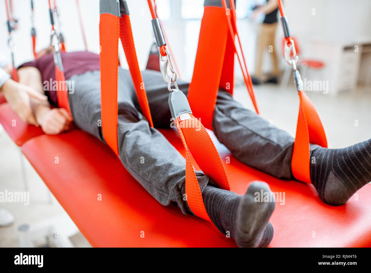 Man hanging on the suspension medical equipment during the spine ...