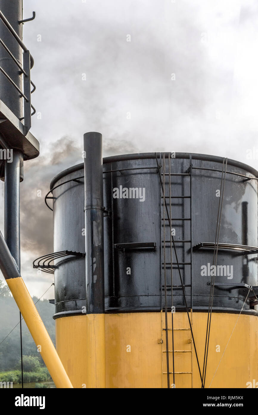 Large, black chimney with ladder and outgoing smoke of an old steamboat ...