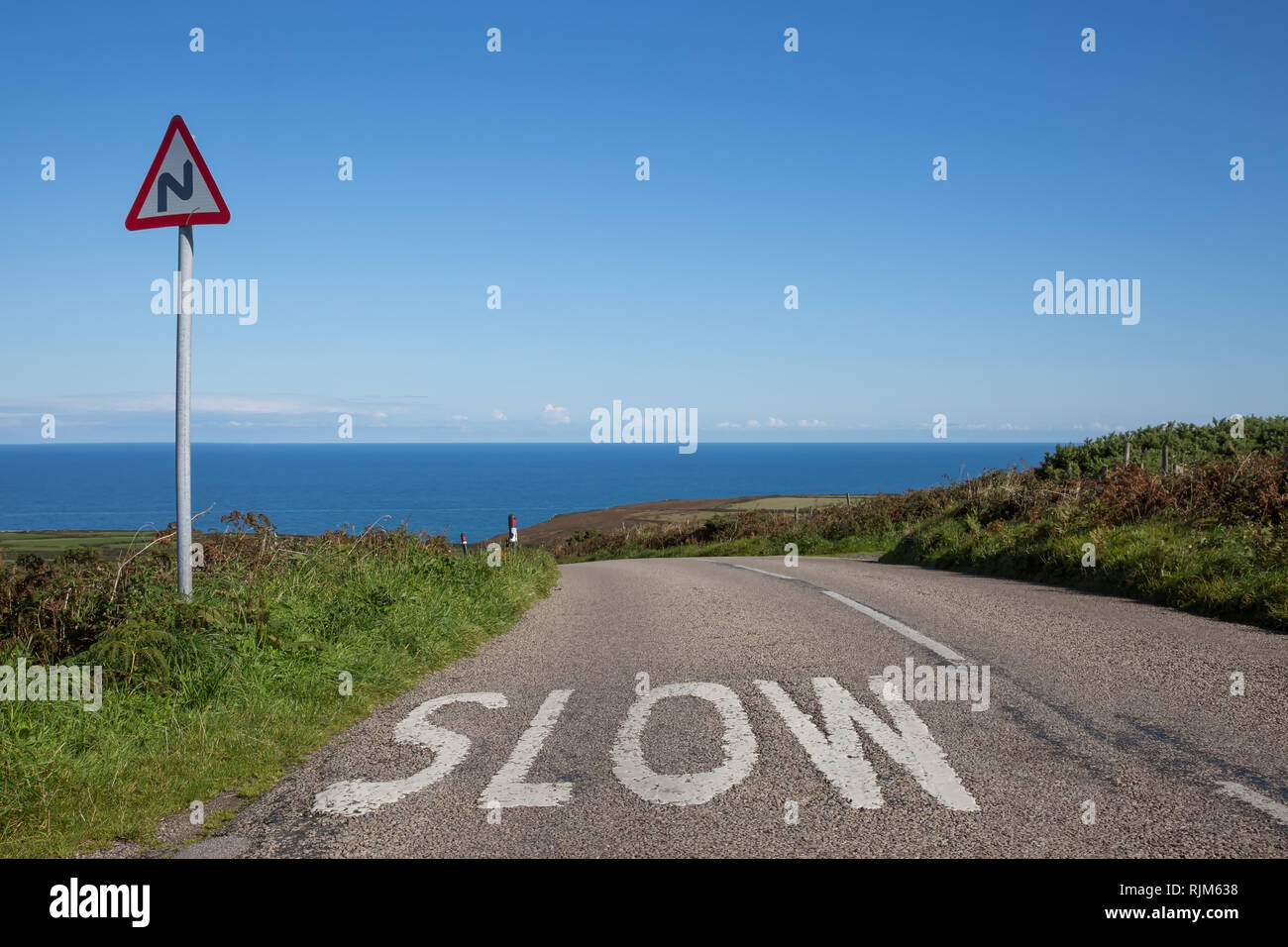 A street to the ocean with a sign and the warning word slow Stock Photo ...