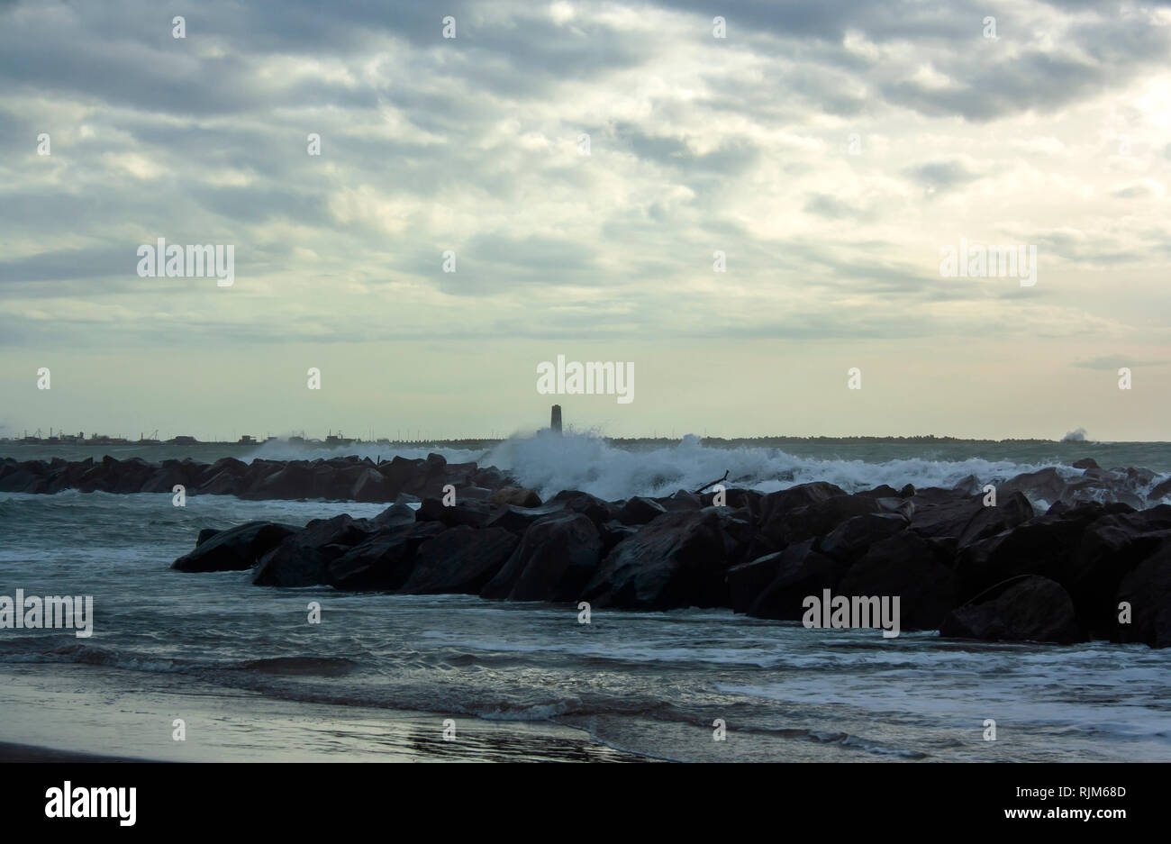 Fiumicino beach shoot in a winter windy day. Sea waves bump into rocks ...