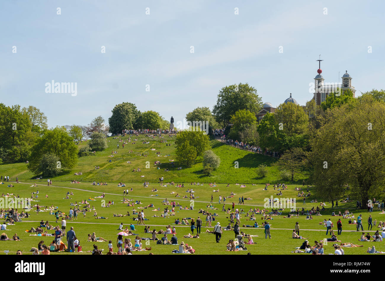 Crowds of people lie on the grass and enjoy the sun and hot weather during a heatwave in ...