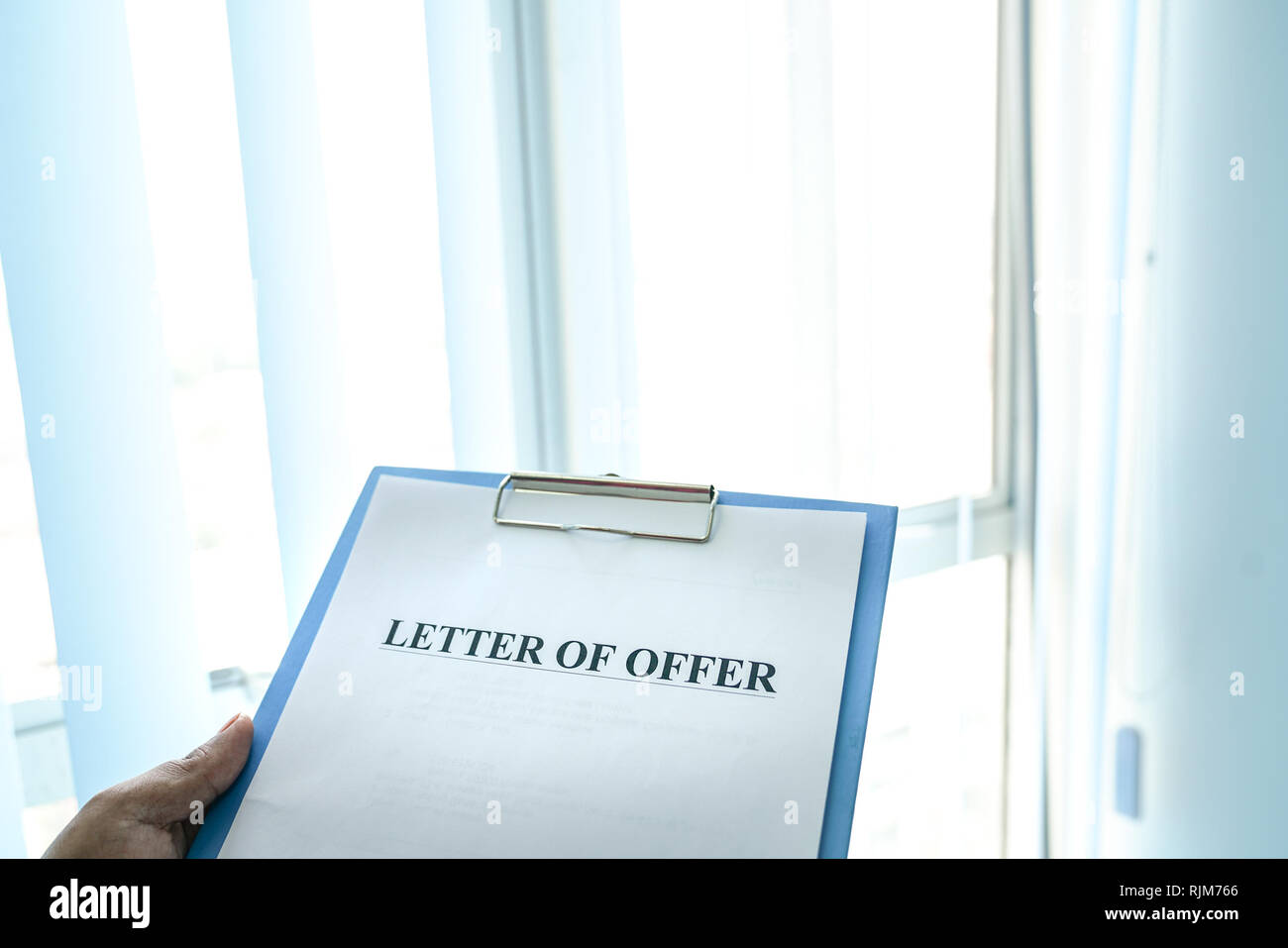 Hand holding letter of offer clipped on a board Stock Photo - Alamy