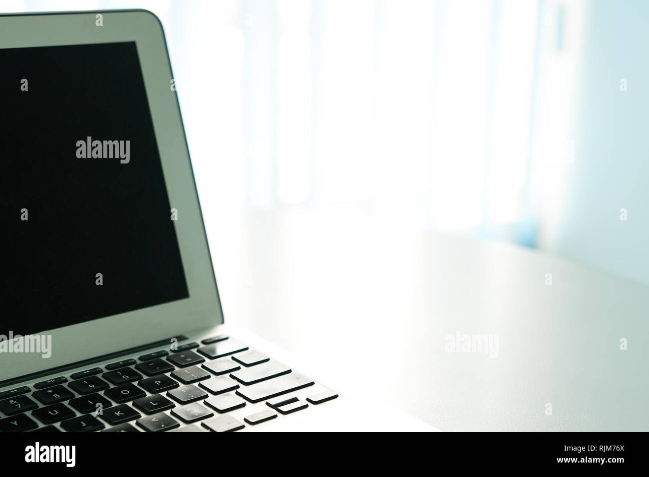 Laptop on office desk with windows at the background Stock Photo - Alamy