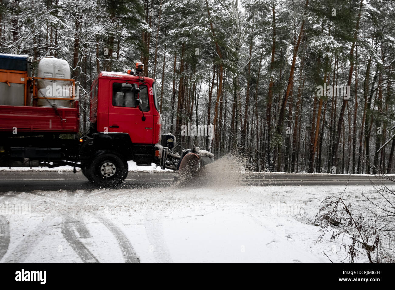Snow plow removing snow dissolving from the roadway and sprinkling salt ...