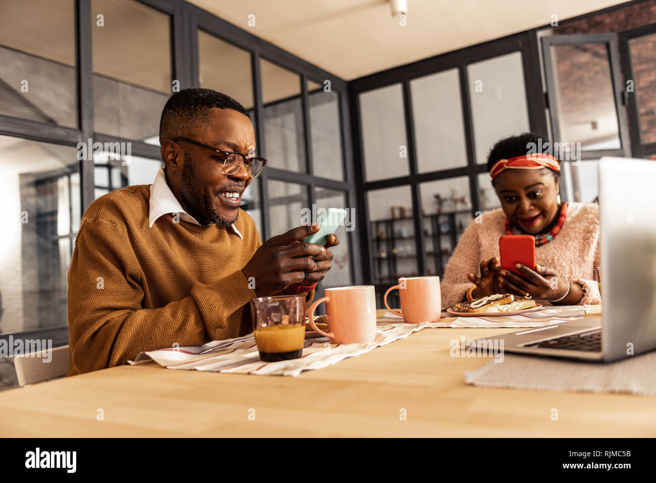 Delighted joyful couple being engaged in their smartphones Stock Photo ...