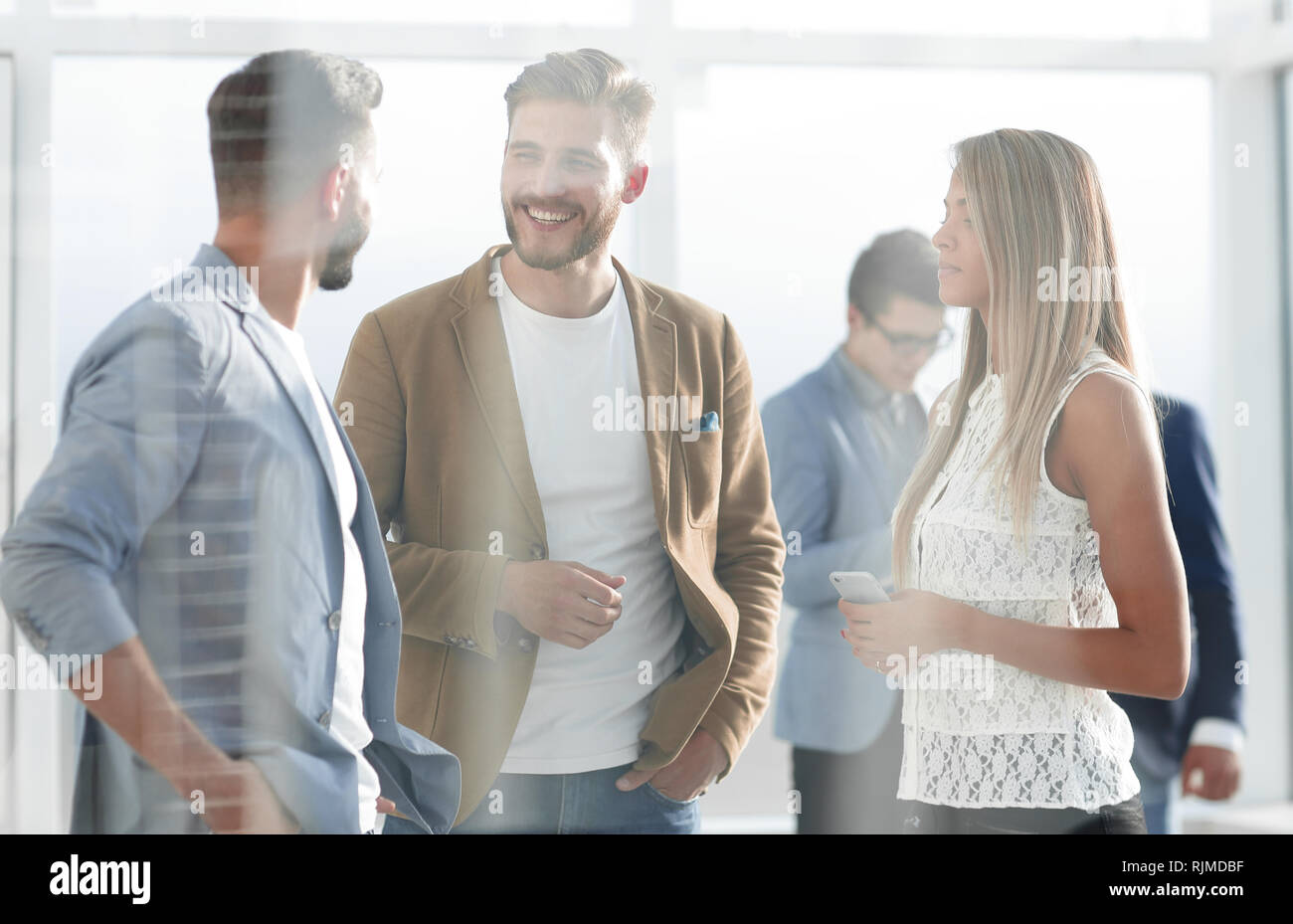 behind the glass.young employees standing in the office Stock Photo - Alamy