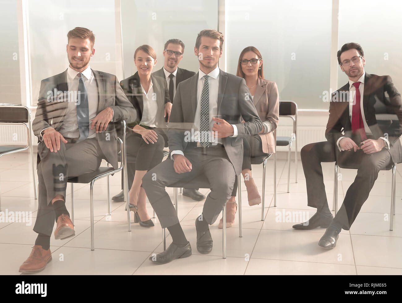 Man and women sitting on chairs in row Stock Photo - Alamy