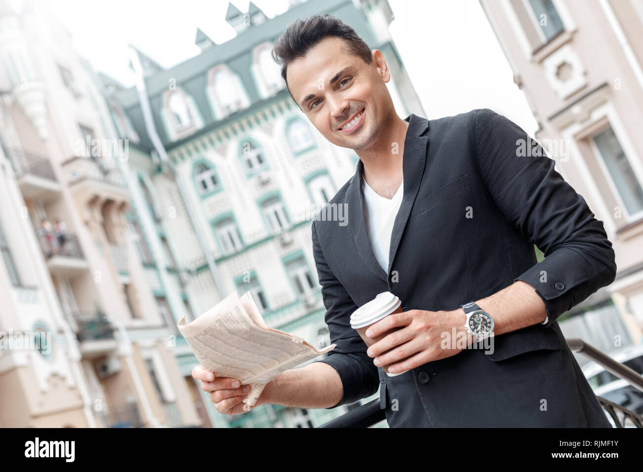 Morning routine. Young man in suit on city street standing with cup of ...