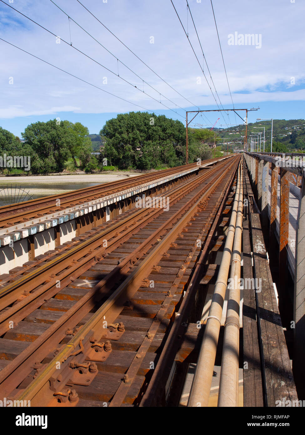 Perspective view along rusty railway tracks crossing a bridge with ...