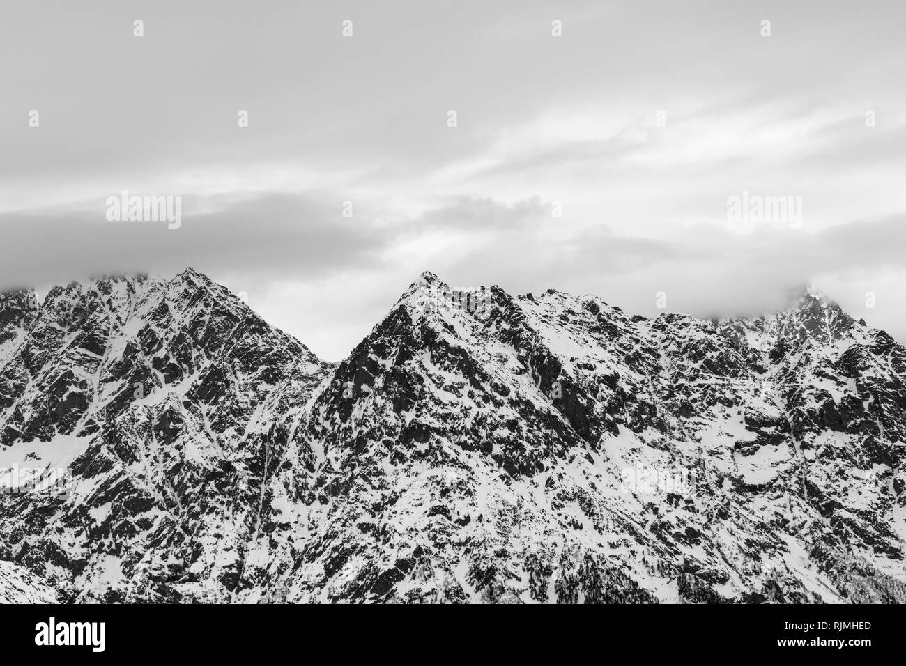Rocky mountains in snow and cloudy gray sky at winter. Caucasus ...