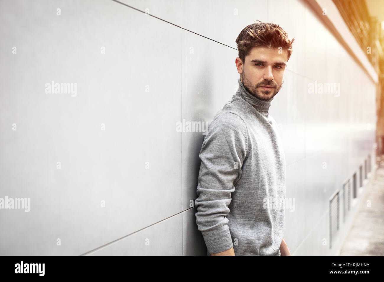 portrait of a cool man posing outside next to a gray modern wall Stock ...