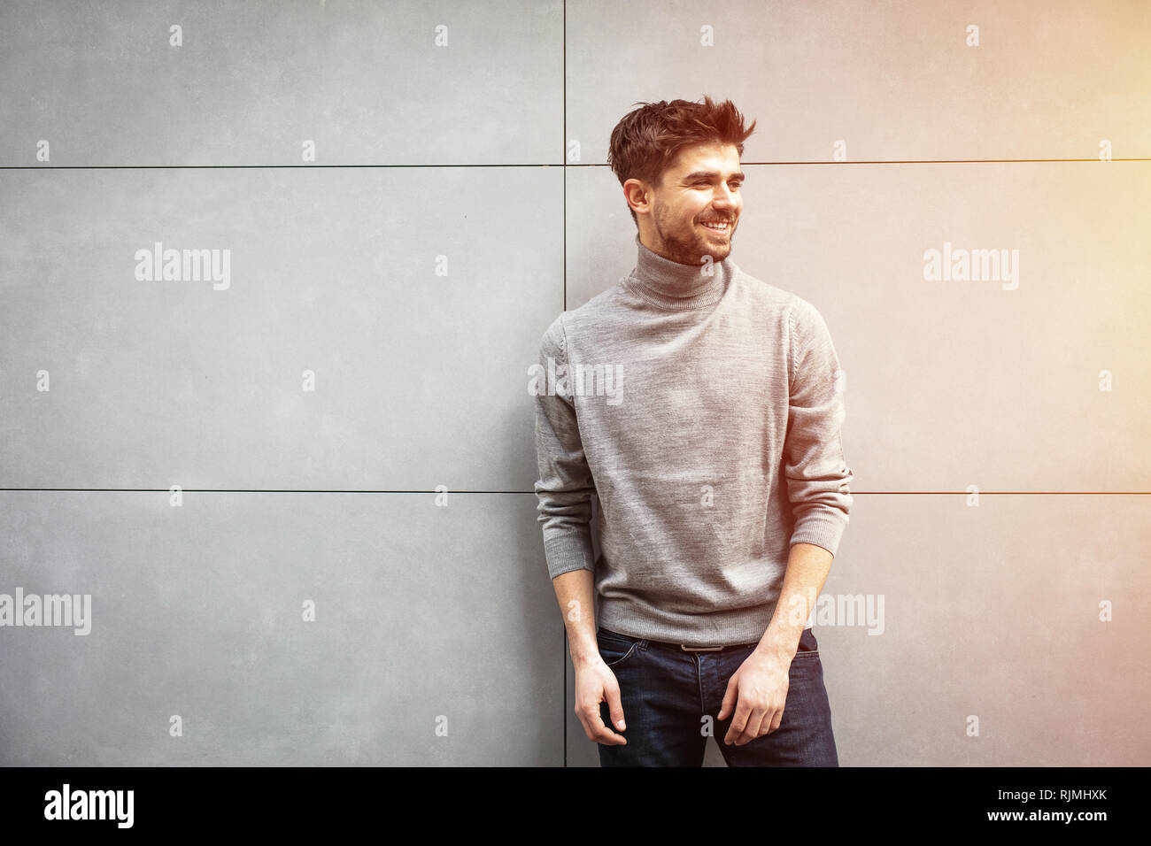 positive and joyfull man posing on a gray modern wall with smile Stock ...