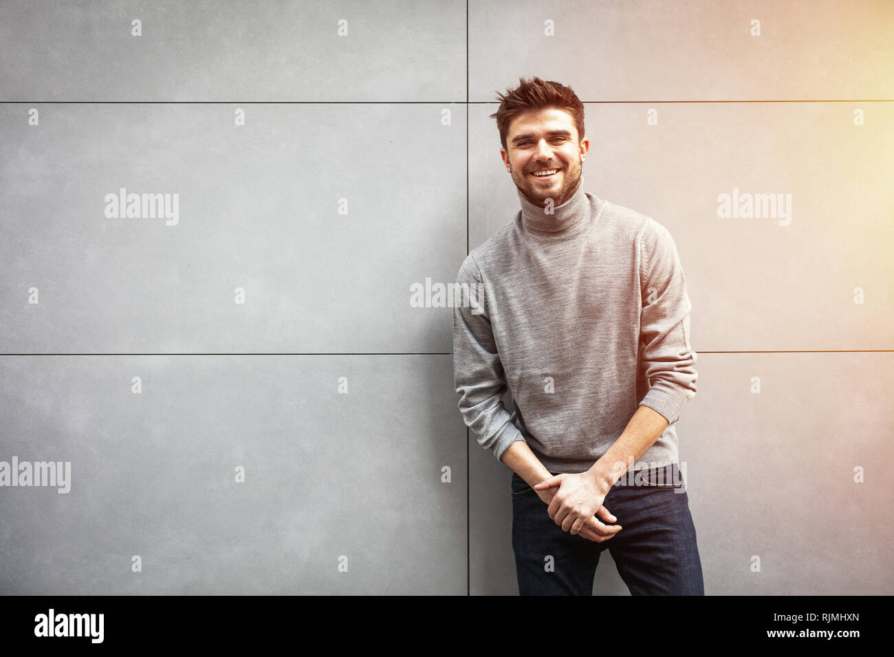 positive and joyfull man posing on a gray modern wall with smile Stock ...