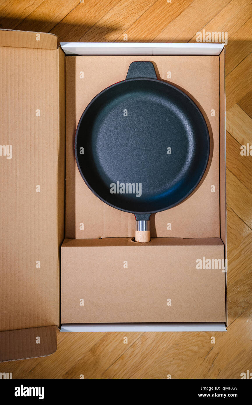 Unboxing of professional black fry pan on kitchen parquet wooden ...