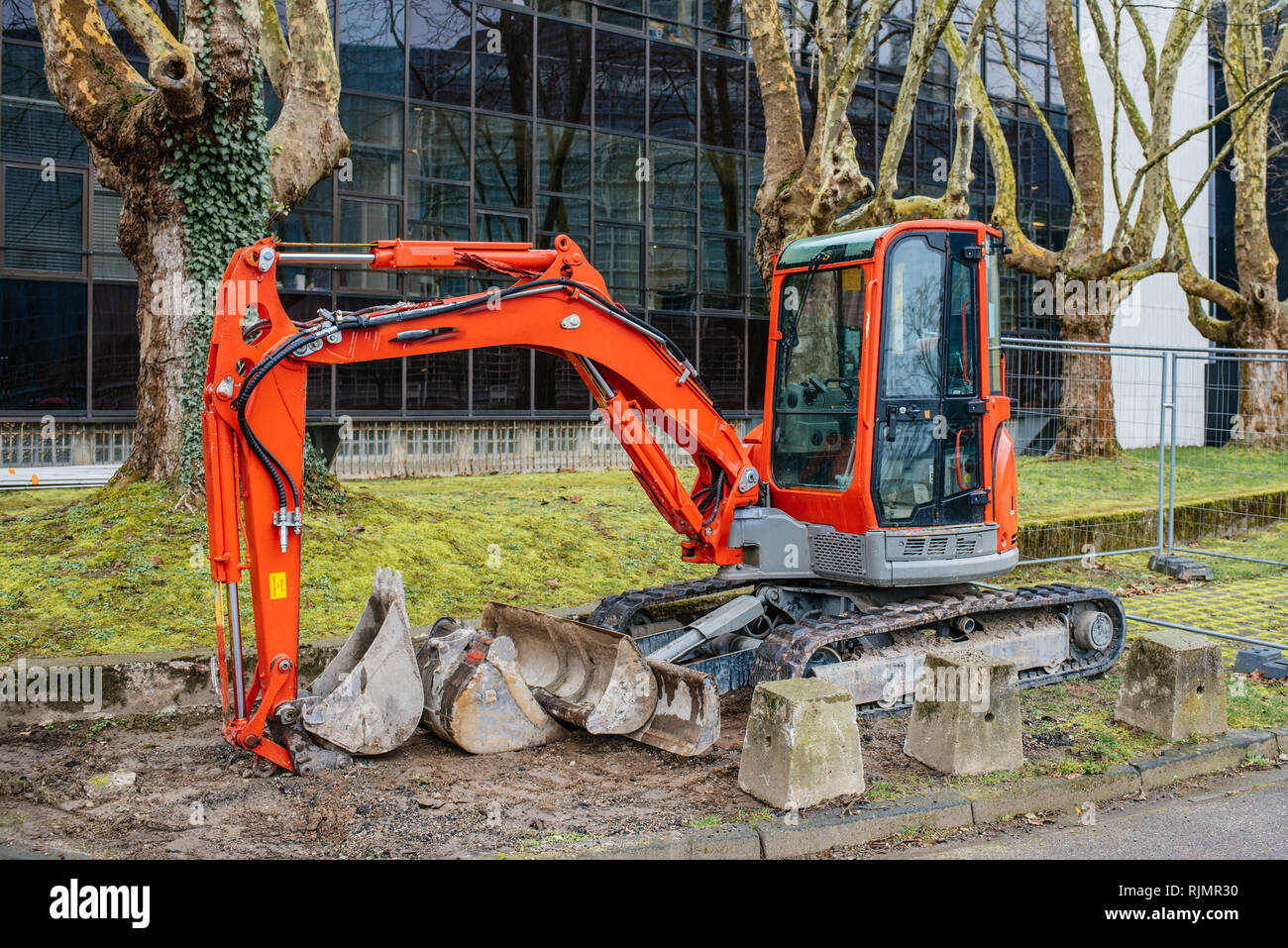 Small machine res excavator on sidewalk during repair works on street ...