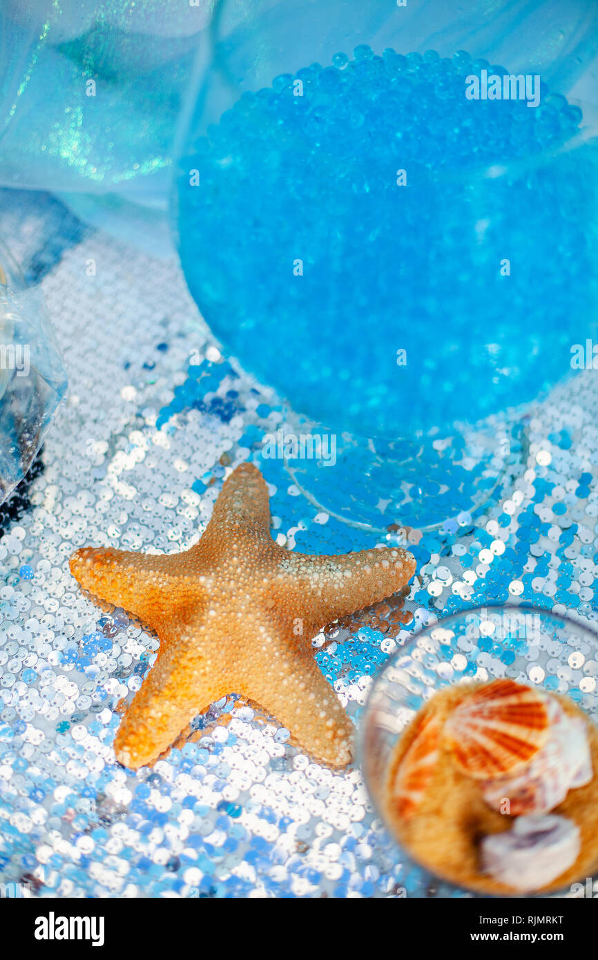 Bright blue balls in the glass vase and dried yellow sea starfish. Sea ...