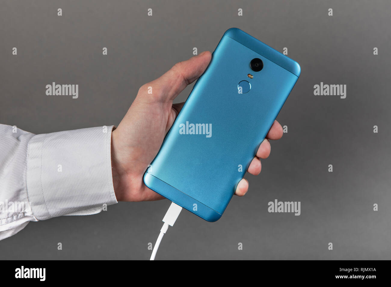 Man's hand holding smartphone with usb cable Stock Photo - Alamy