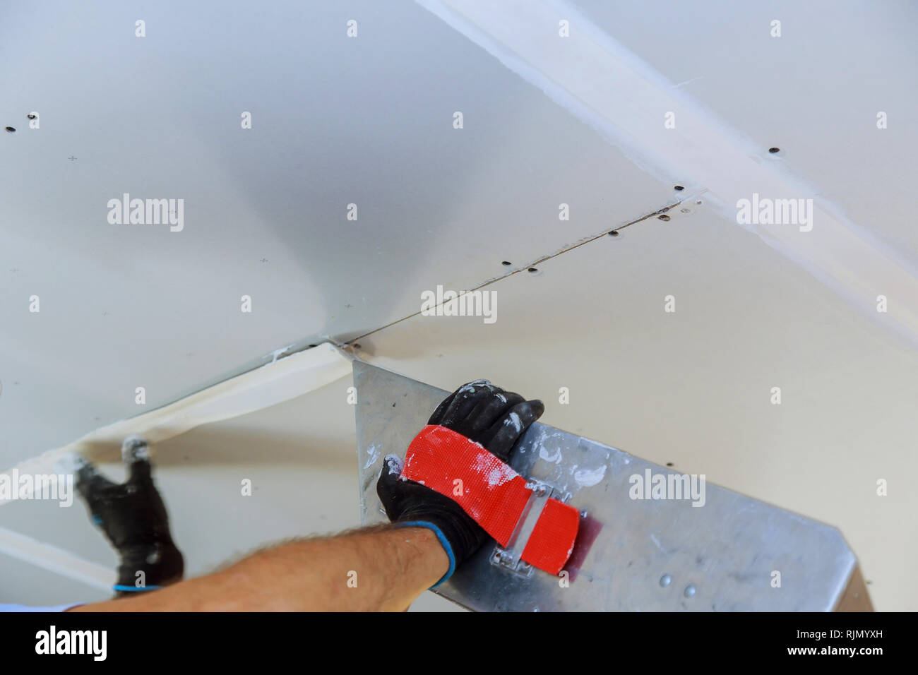 Hand of worker with plaster to gypsum board installing gypsum board ...