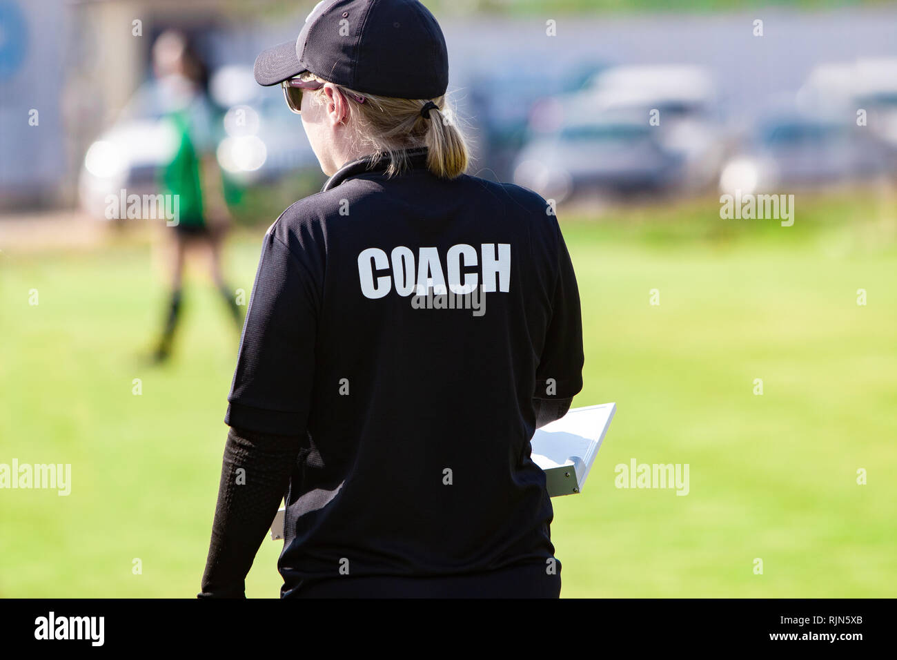 Back view of female football coach in black COACH shirt at an outdoor ...