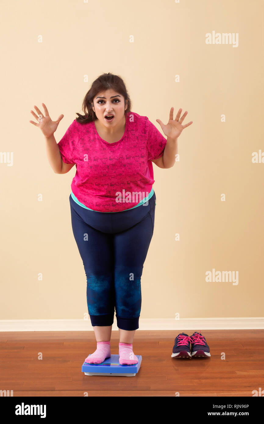 Shocked Overweight Woman Standing On Measuring Scale Stock Photo - Alamy