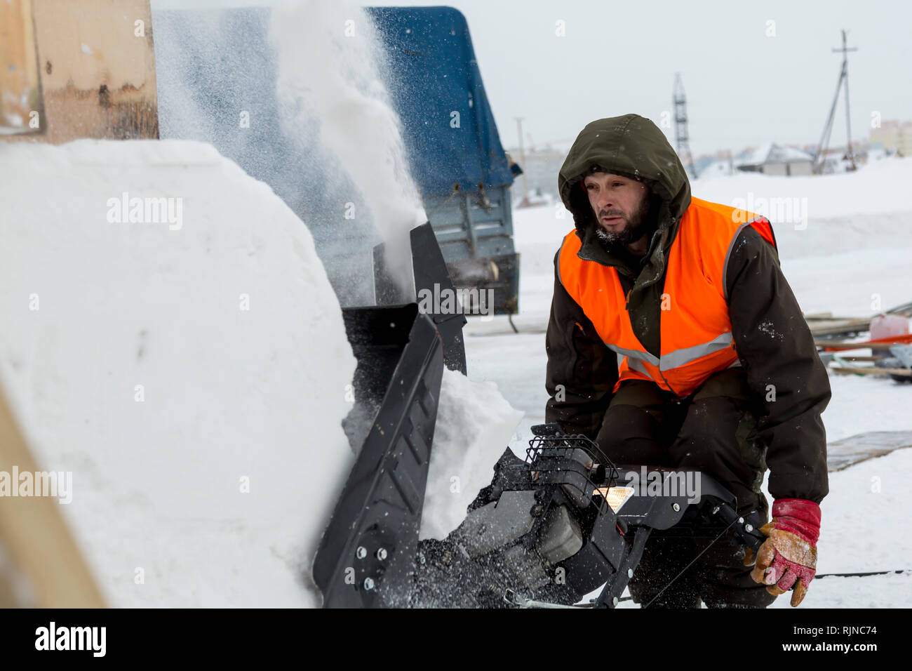 Worker removes snow in a blizzard using a snowplow Stock Photo - Alamy