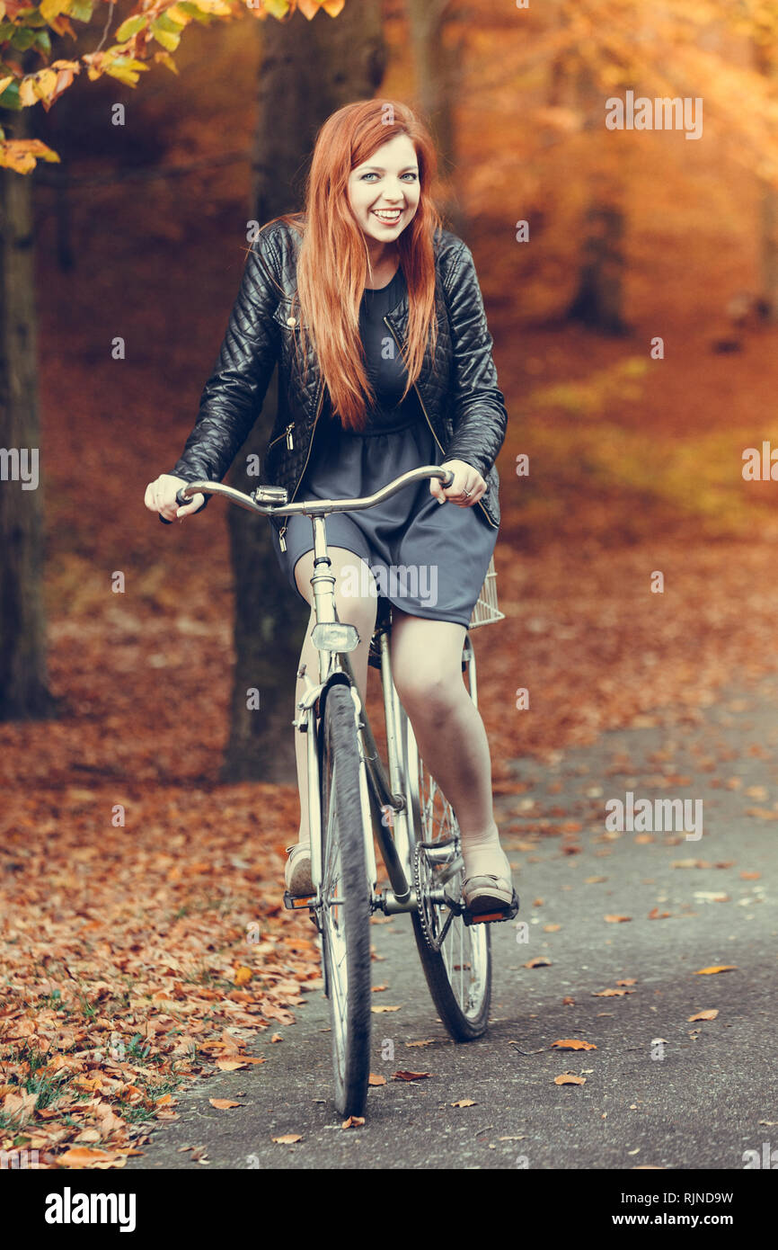 Woodland nature outdoor relax leisure concept. Redhead lady cycling in ...