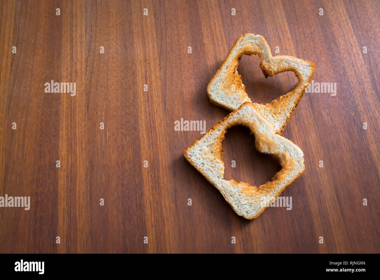 Toasted white bread toasts with heart shape on brown wooden background ...