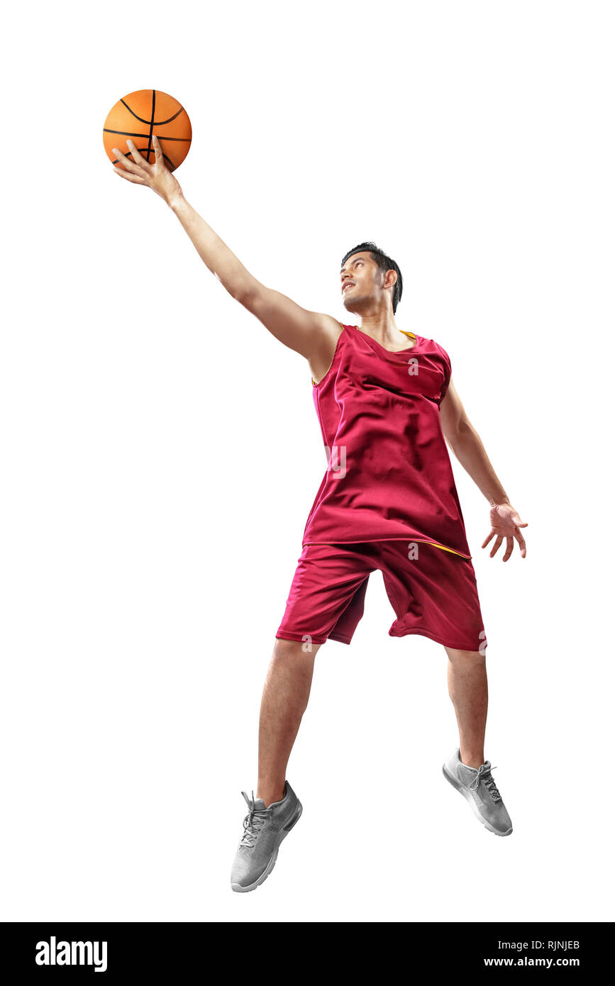 Attractive asian basketball player man in red uniform jumping with ball ...
