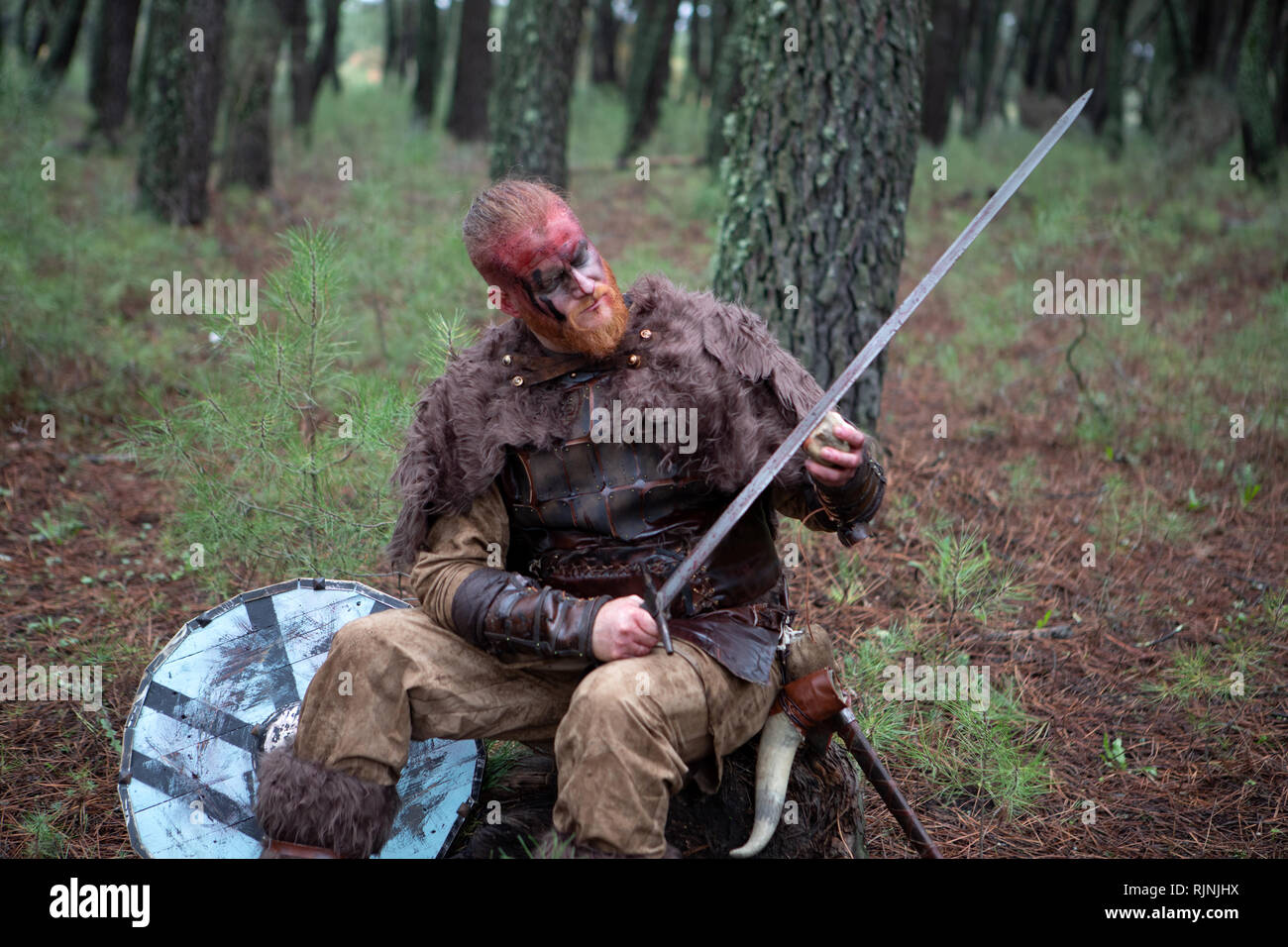 Real viking sharpening his sword with a stone. Ready for the fight ...