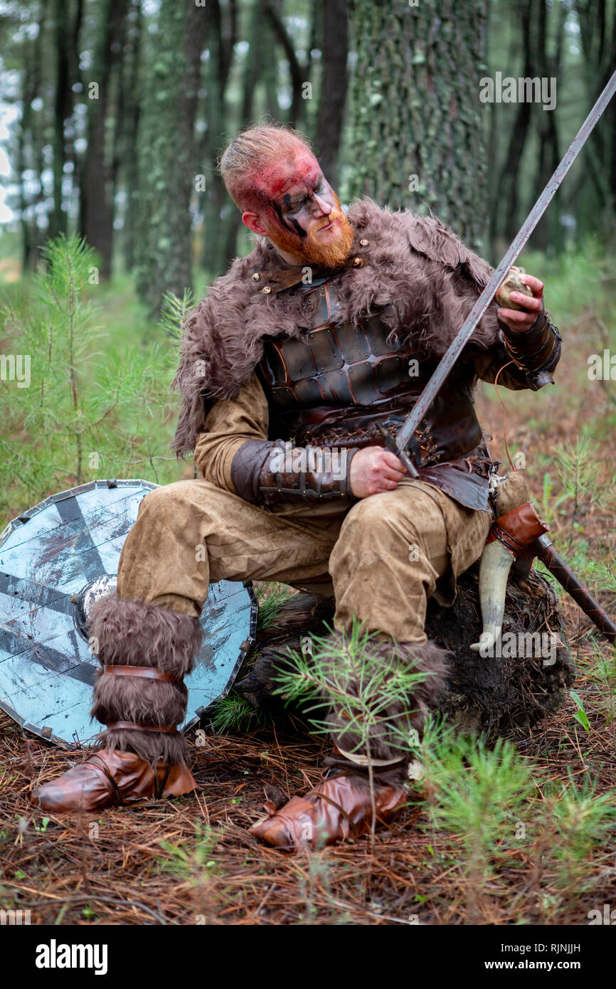 Real viking sharpening his sword with a stone. Ready for the fight ...