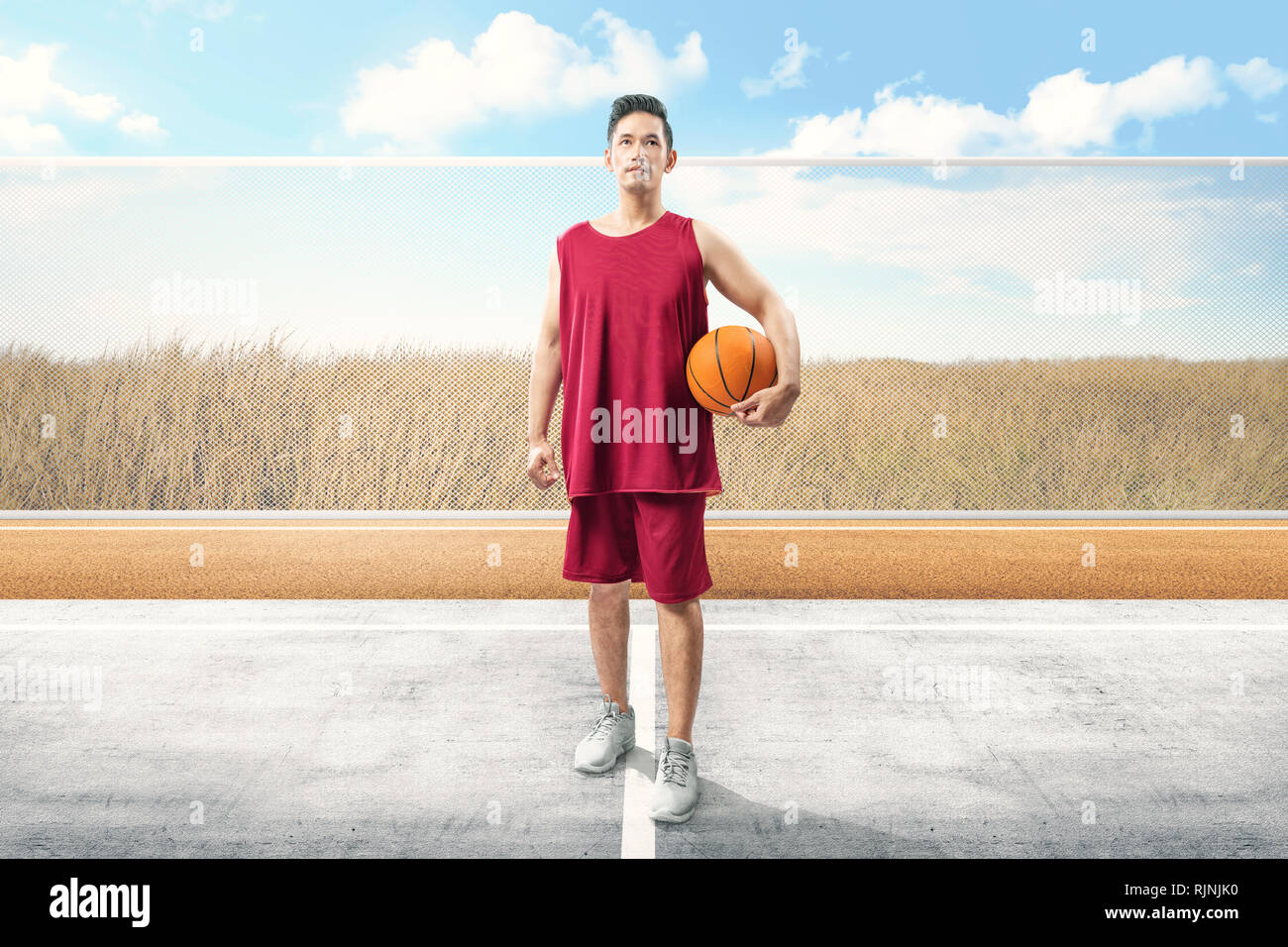 Handsome asian man with sport uniform carrying the ball on the outdoor ...
