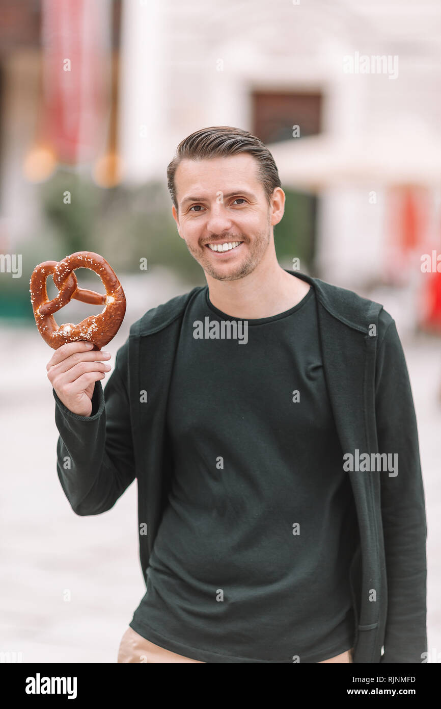 Beautiful young man eating pretzel outdoors in Europe Stock Photo - Alamy