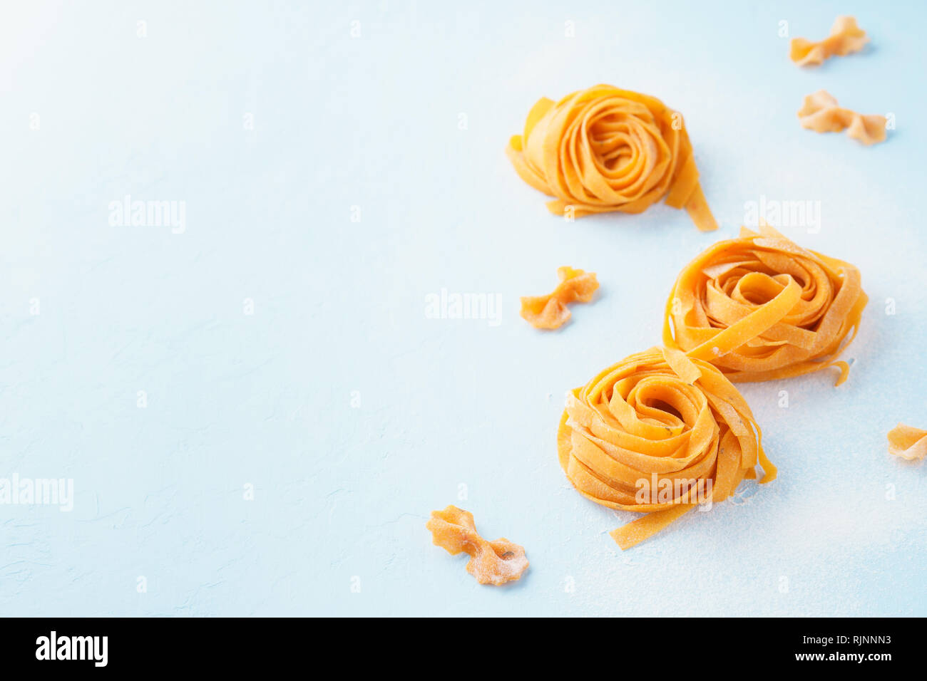 Fresh uncooked homemade vegan pasta on light blue background. Healthy ...