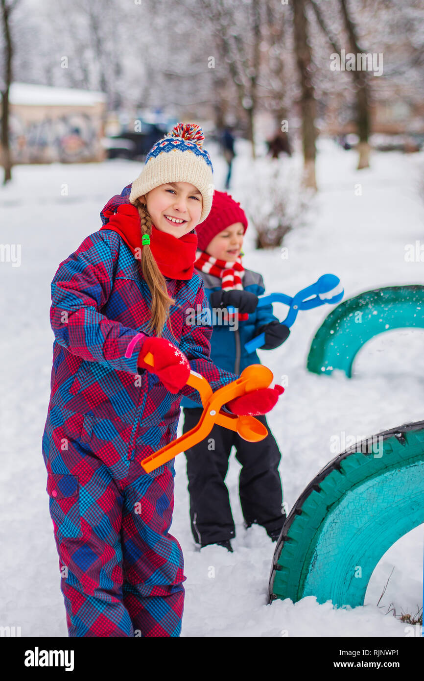 Happy brother and sister play snowballs on a winter walk, making ...