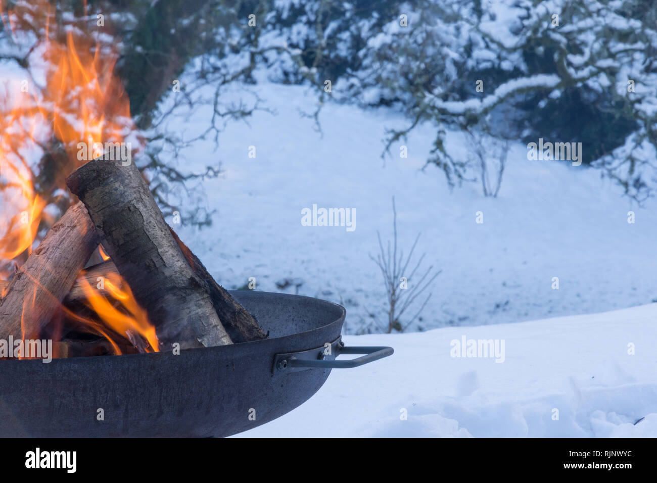 Firepit in the snow with log fire Stock Photo - Alamy