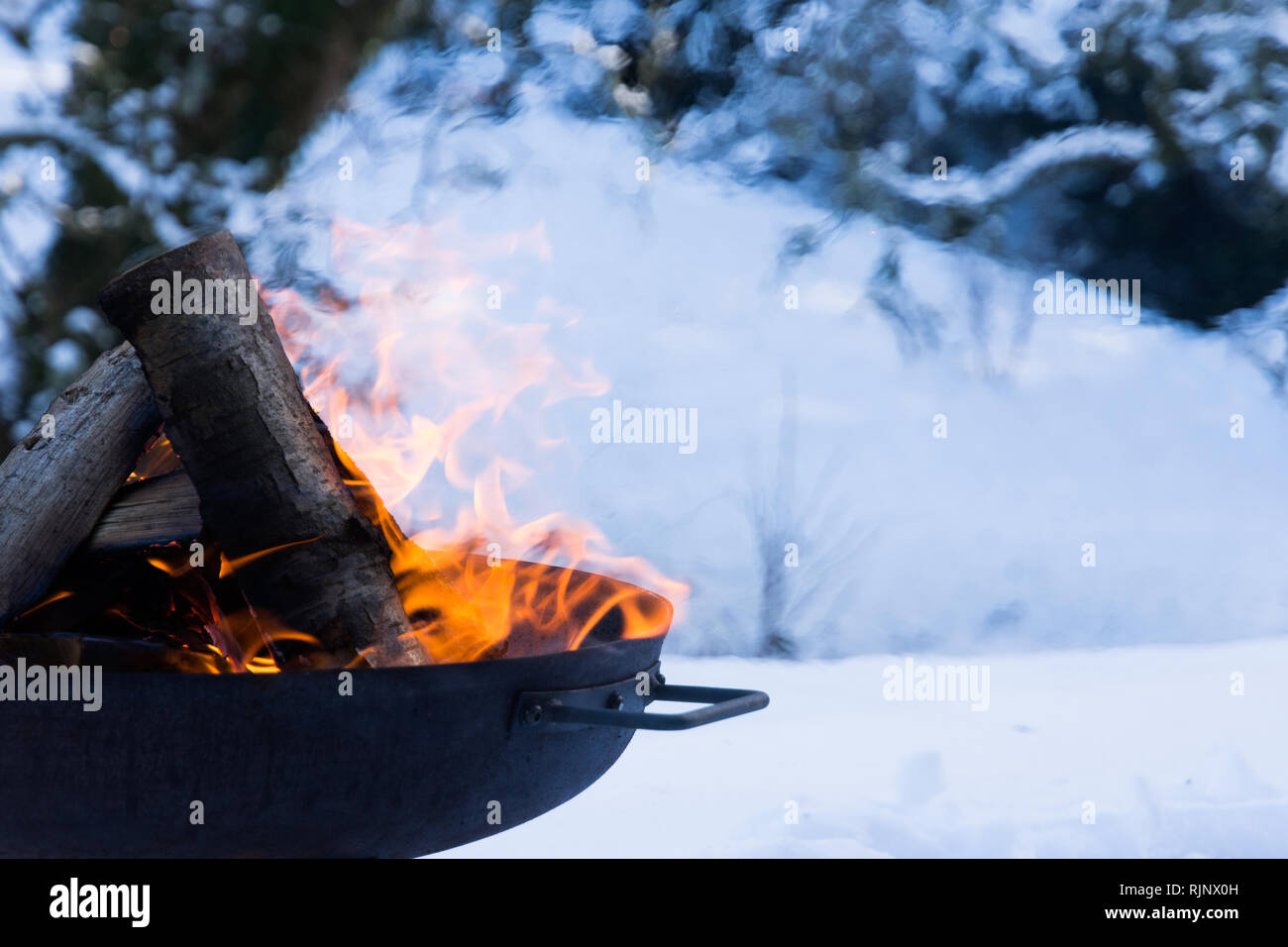 Firepit in the snow with log fire Stock Photo - Alamy
