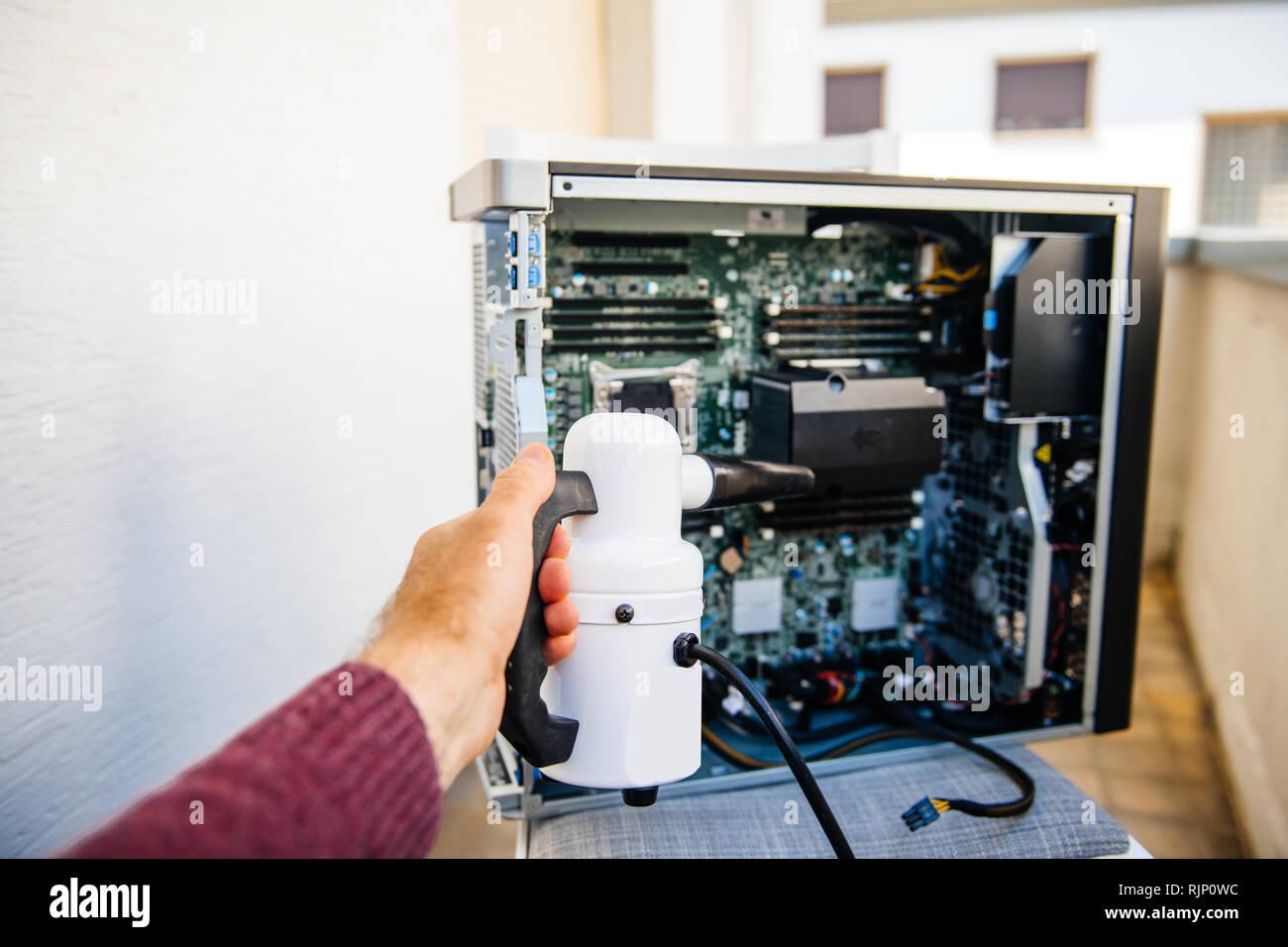 Man hand holding vacuum pump to clean computer case on balcony from the ...