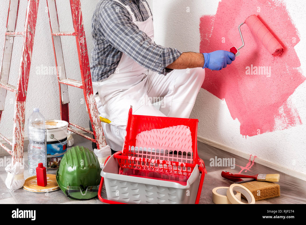 Caucasian house painter worker in white work overalls, with the roller ...
