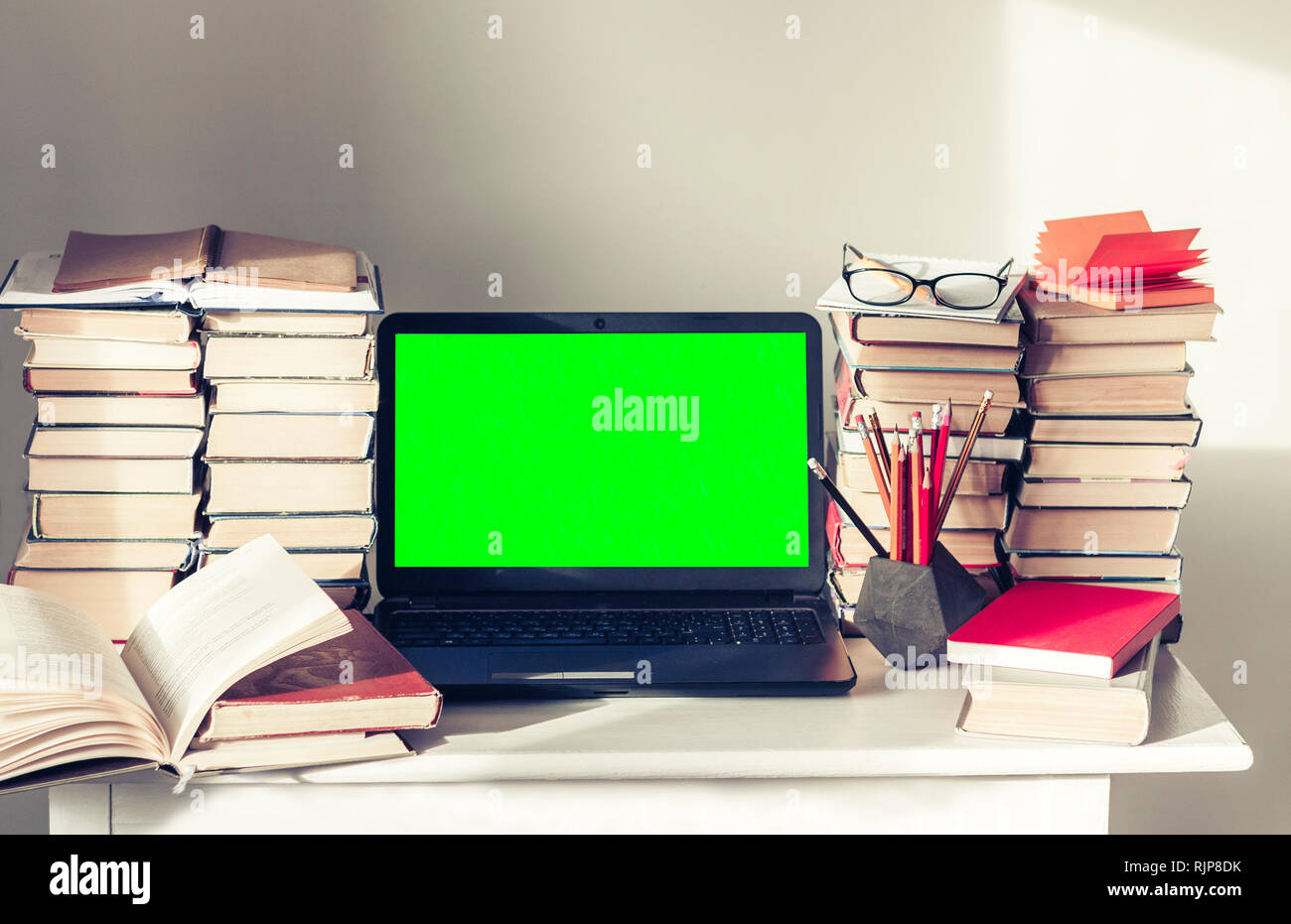 Green screen laptop, stack of books, notebooks and pencils on white ...