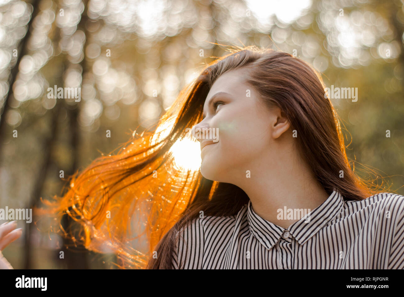 Portrait of a brown-haired girl whose sunset sunlight shimmers in her ...
