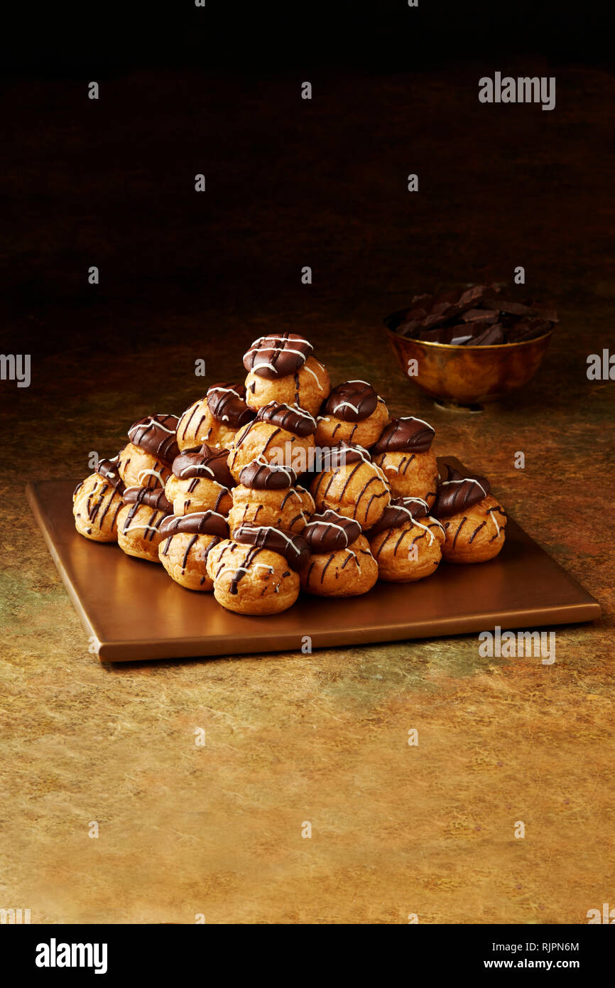 Still life with stacked chocolate profiteroles on gold plate, christmas ...