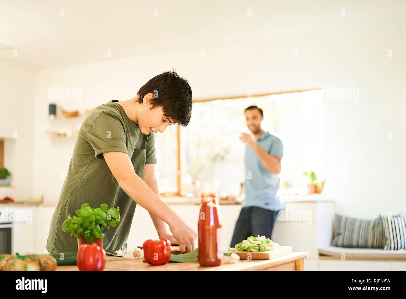 Boy preparing food at kitchen counter, father watching Stock Photo - Alamy