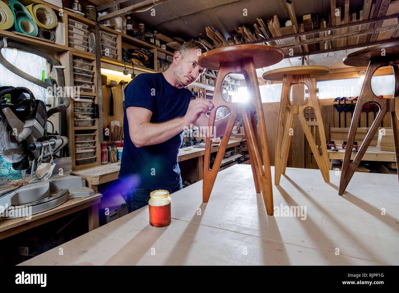 Craftsman polishing wooden stool with oil finish Stock Photo - Alamy