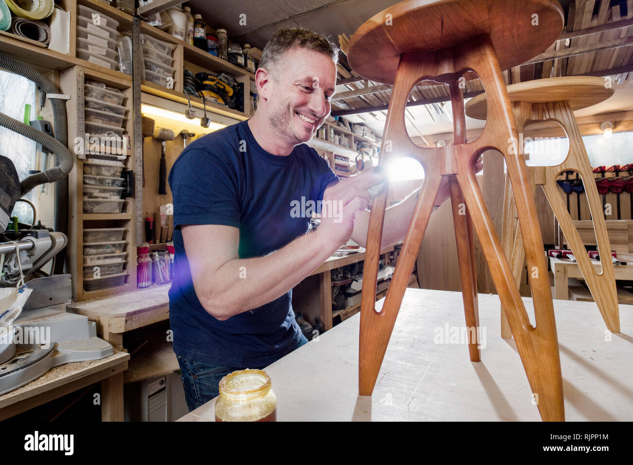 Craftsman polishing wooden stool with oil finish Stock Photo - Alamy