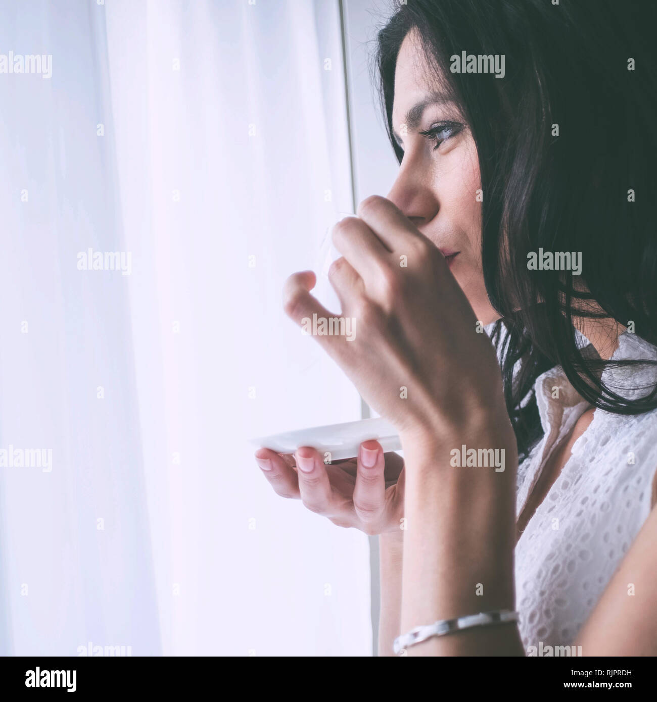 Woman drinking coffee beside window Stock Photo - Alamy