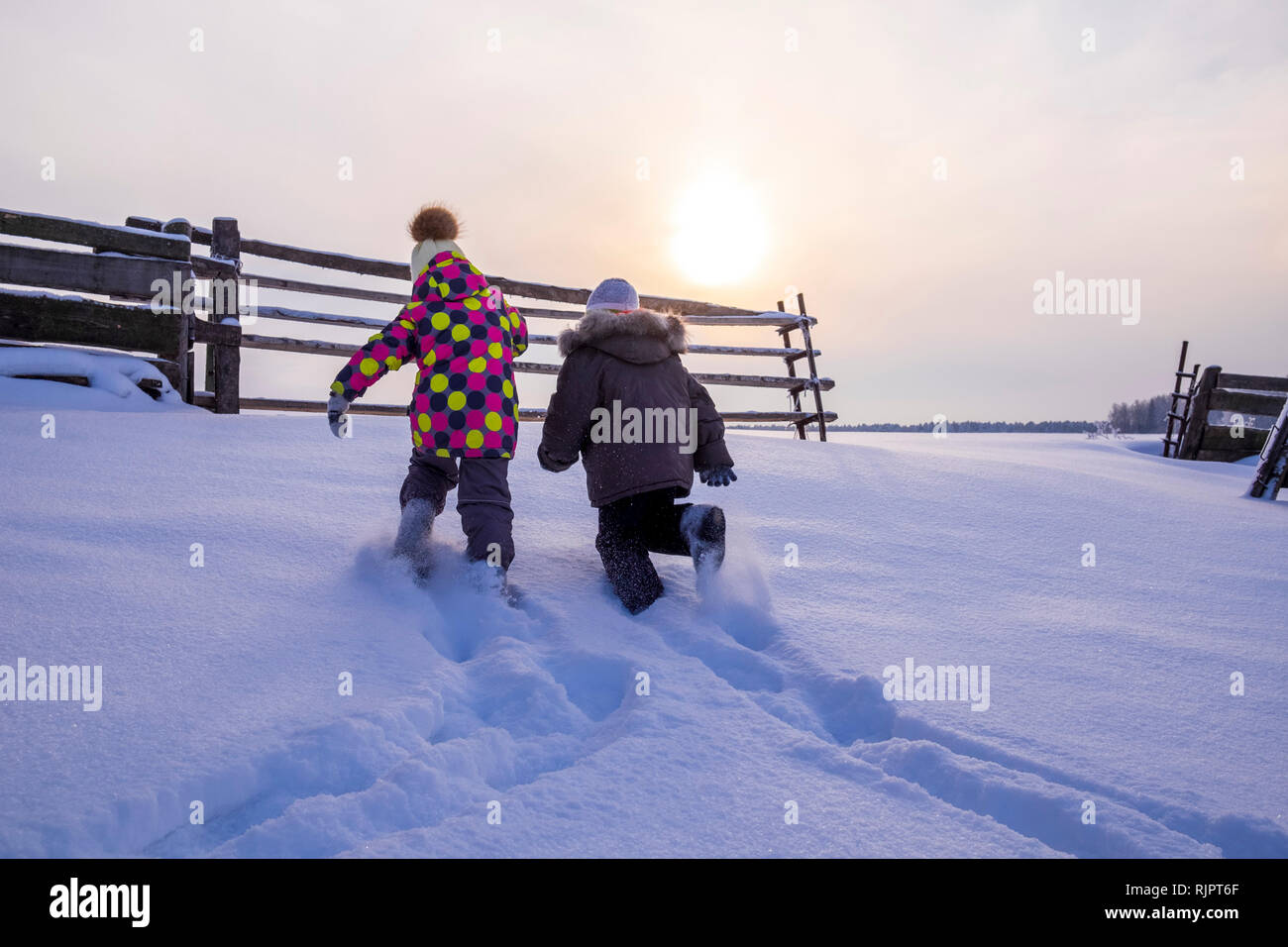 Boy and girl trudging through snow covered landscape, rear view Stock ...
