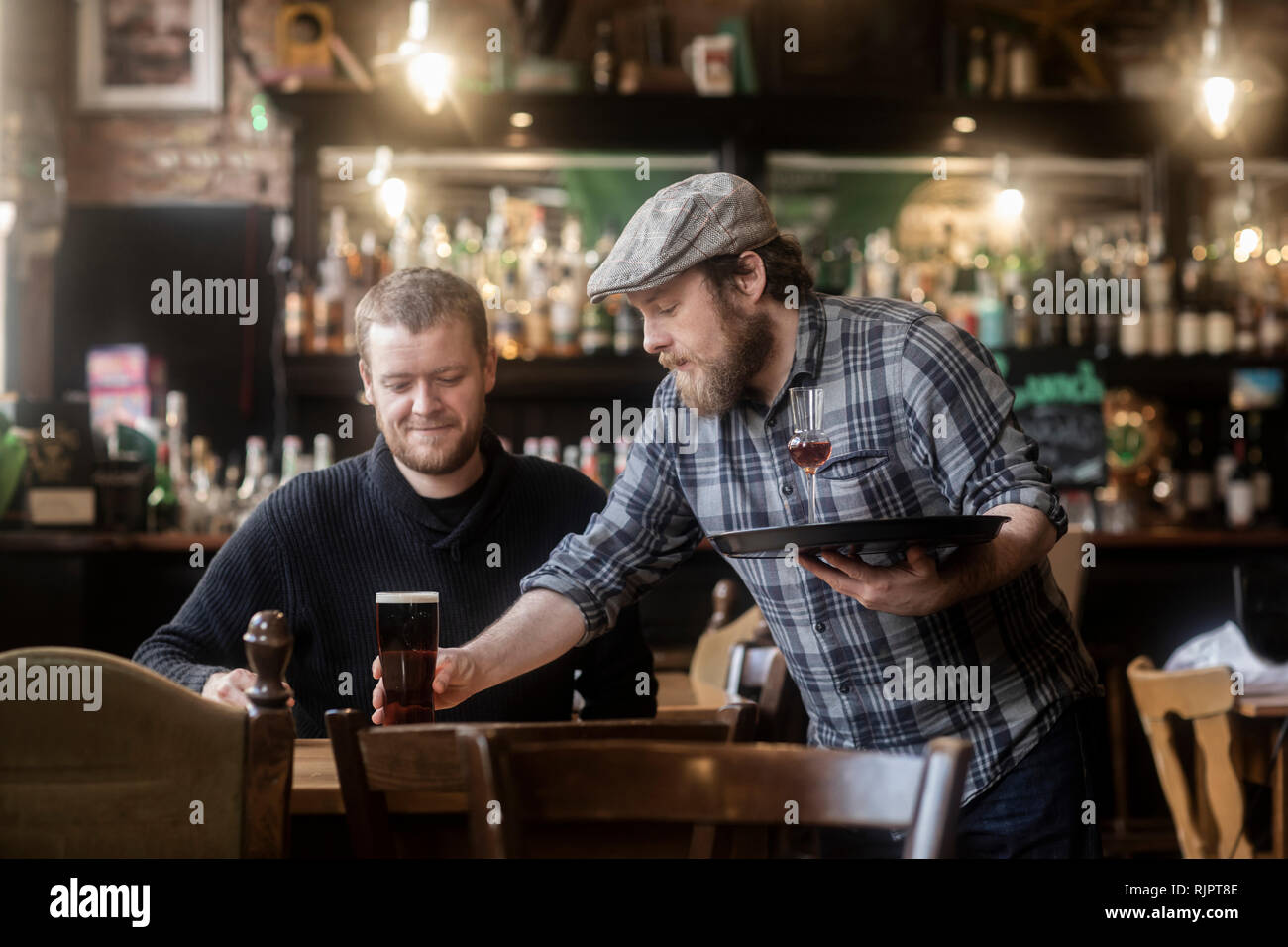 Barman serving beer to customer in traditional Irish public house Stock ...