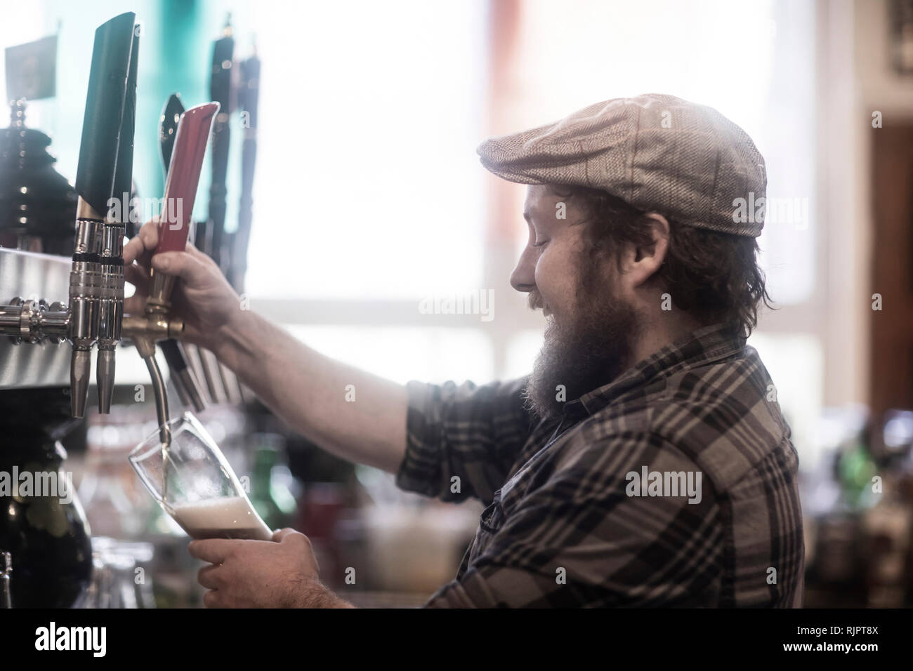 Barman pouring beer from pump in traditional Irish public house Stock ...